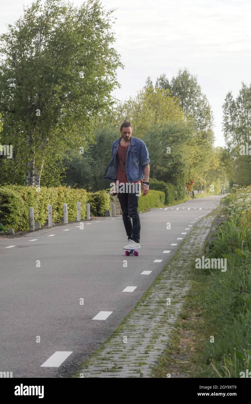 A man face the camera while riding a skateboard on an empty road Stock ...