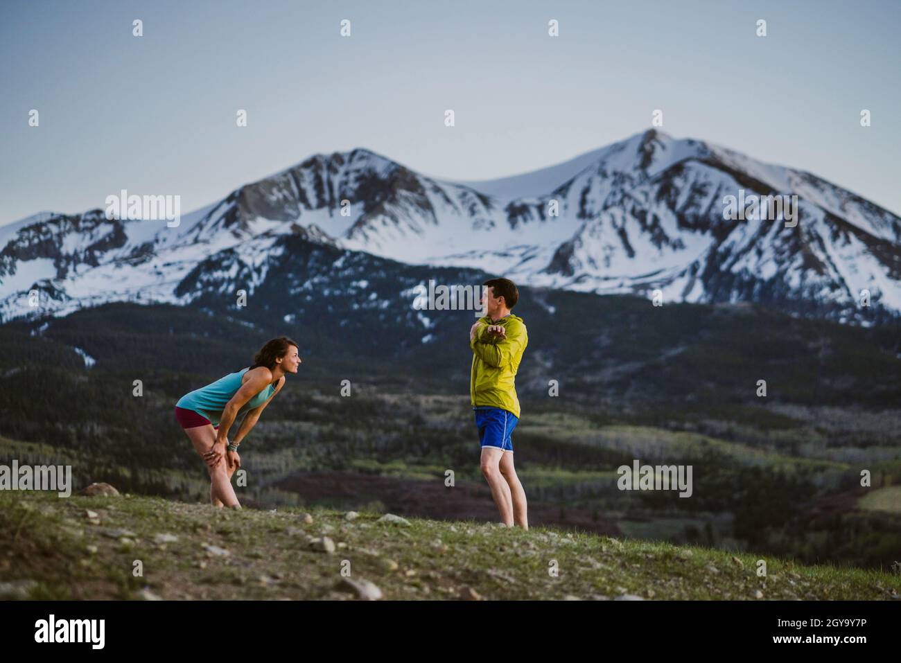Two friends stretch together before trail running in the mountains ...