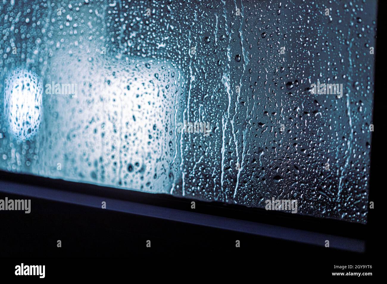 Close up of rain drops on the window in rainy night, cool lights and ...