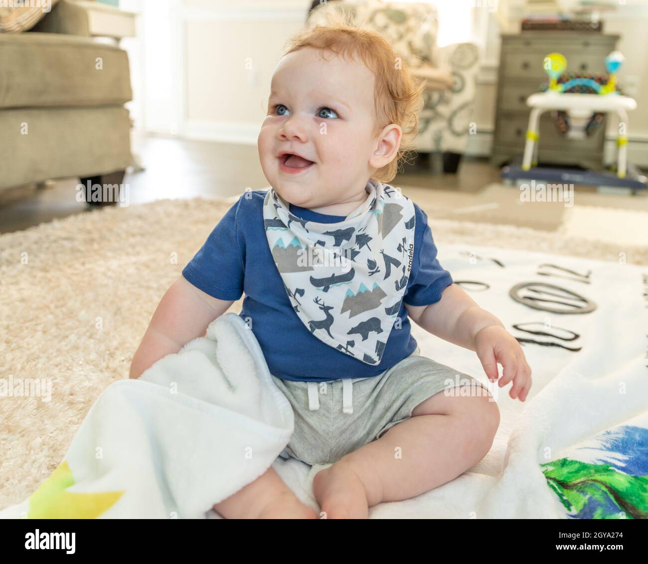 Happy baby boy sitting on floor looking up and smiling Stock Photo - Alamy