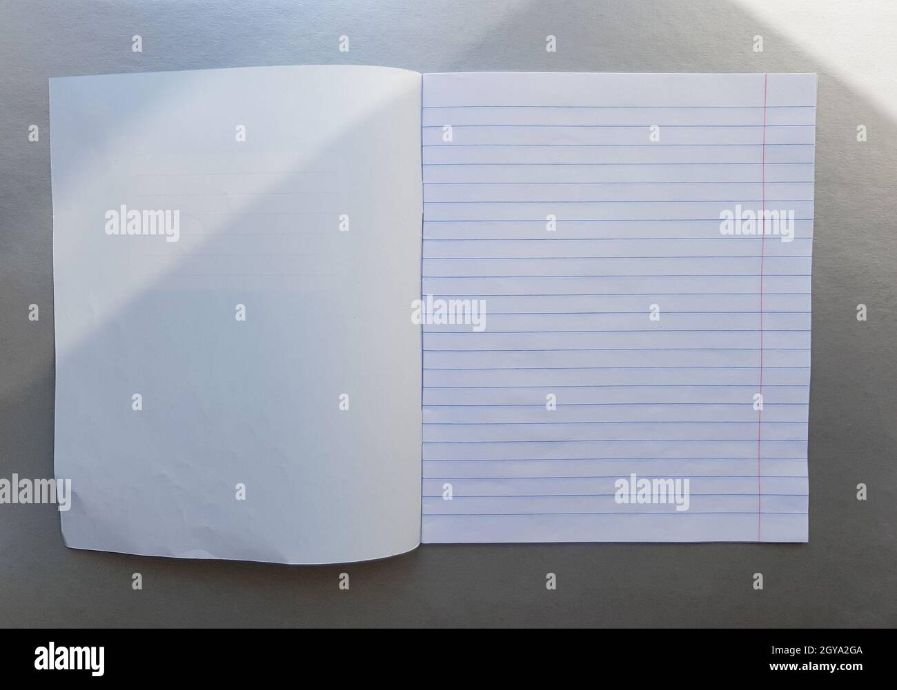 open school notebook with pen on a gray desk with sun rays from the ...