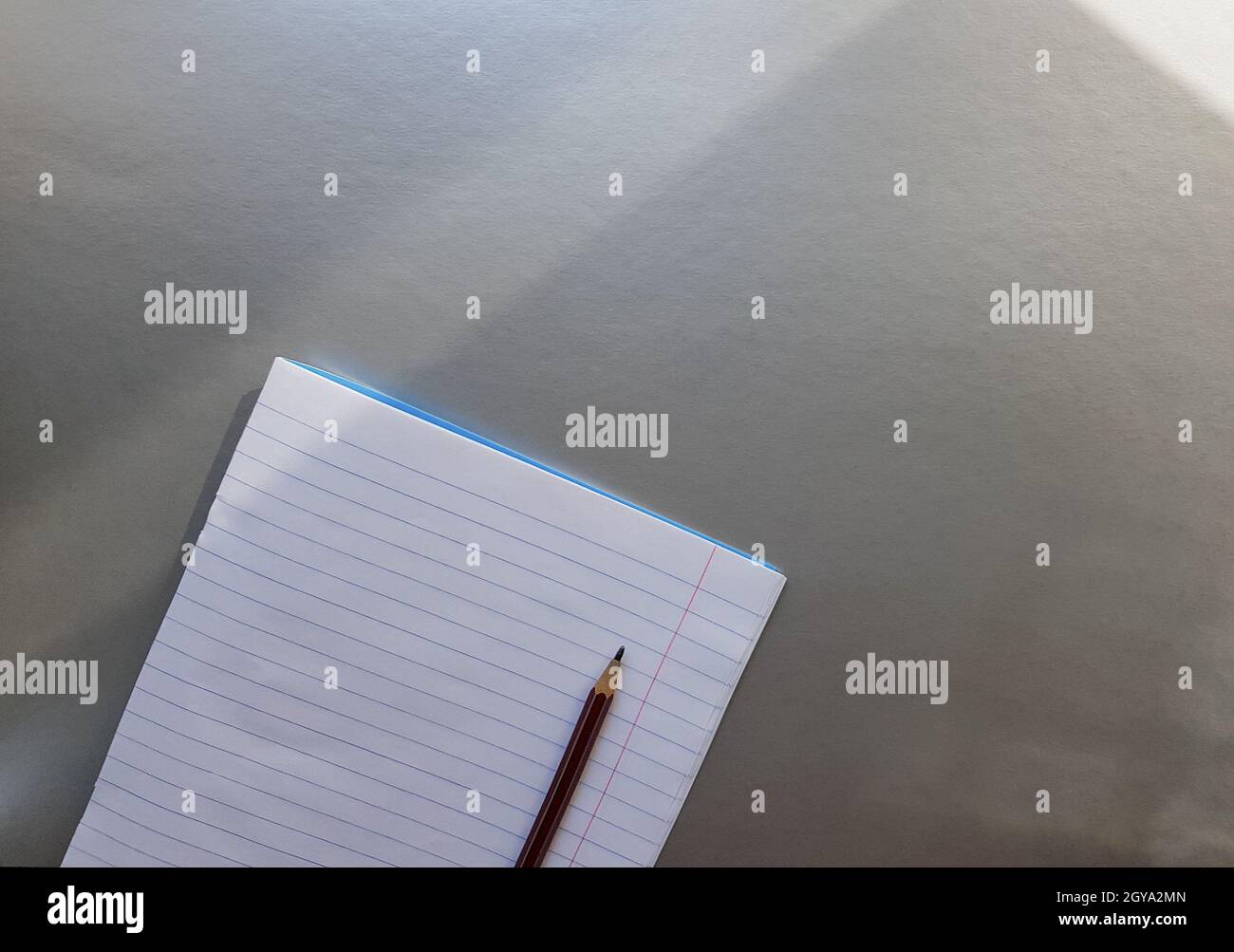 open school notebook with pen on a gray desk with sun rays from the ...