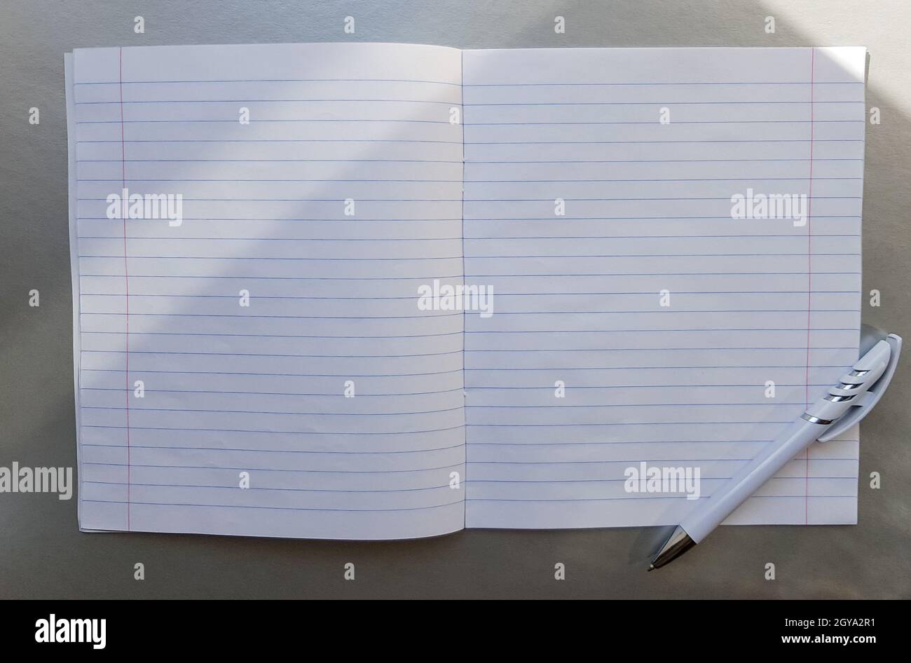 open school notebook with pen on a gray desk with sun rays from the ...