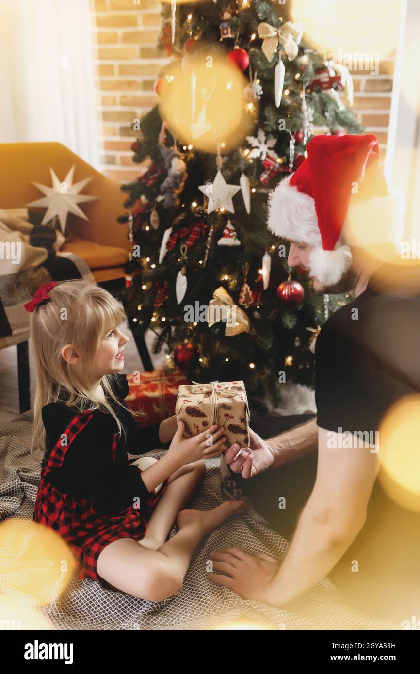Young father in red Santa hat giving Christmas gift to his smiling ...