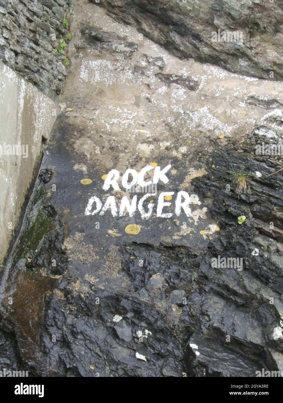 Vertical closeup of a rustic wall with "rock danger" written on it with ...