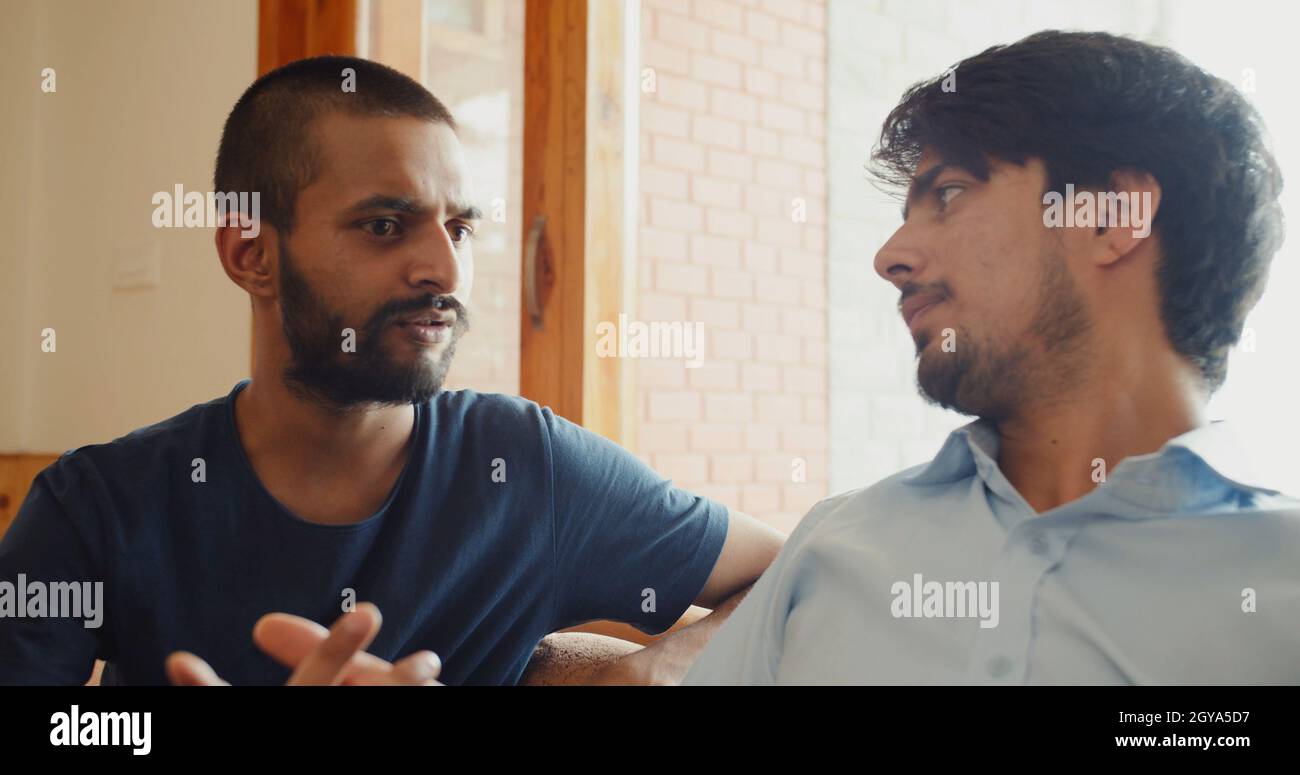 Close up shot of two South Asian men sitting and talking to each other ...