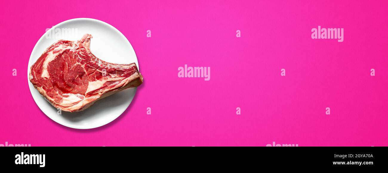 Raw beef prime rib and plate isolated on pink background. Top view ...