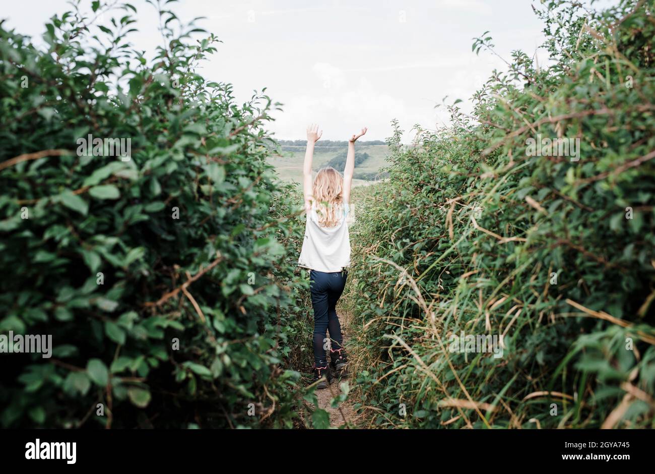 girl walking through bushes keeping her arms up in the countryside ...