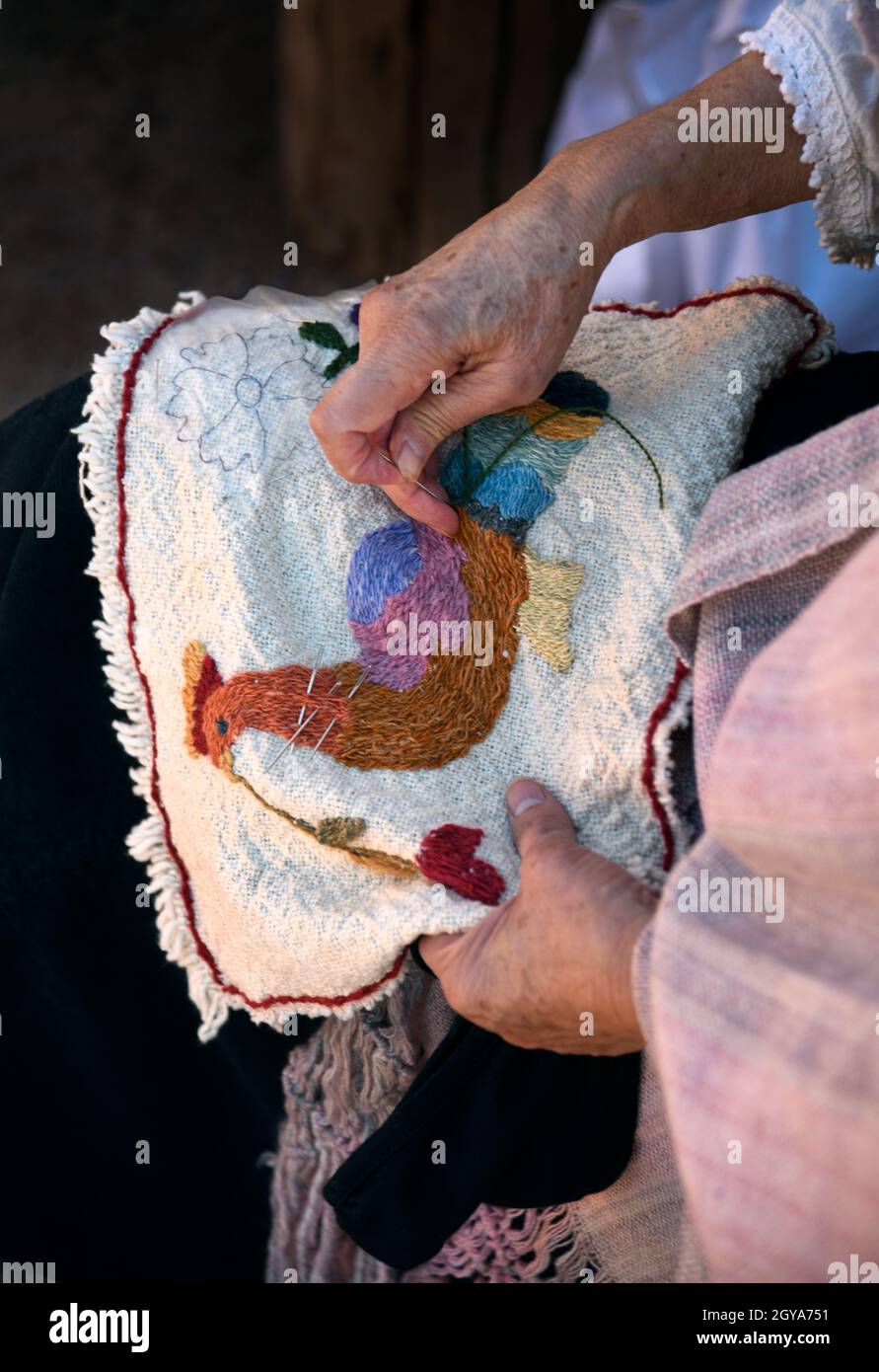 A woman stitches a traditional hispanic colcha embroidery textile at El ...