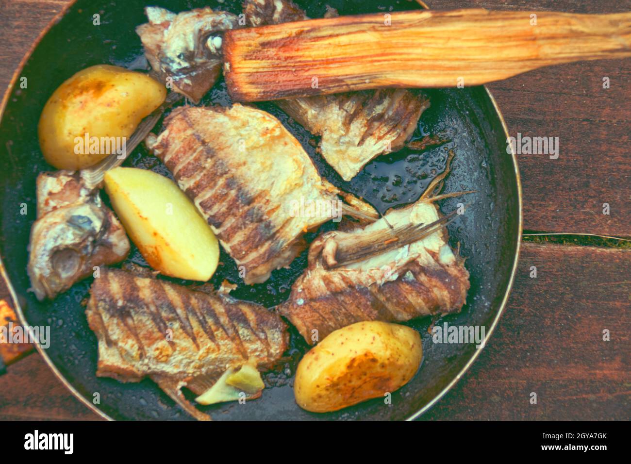 Field food. Fried fish and jacket potato in a frying pan with a ...