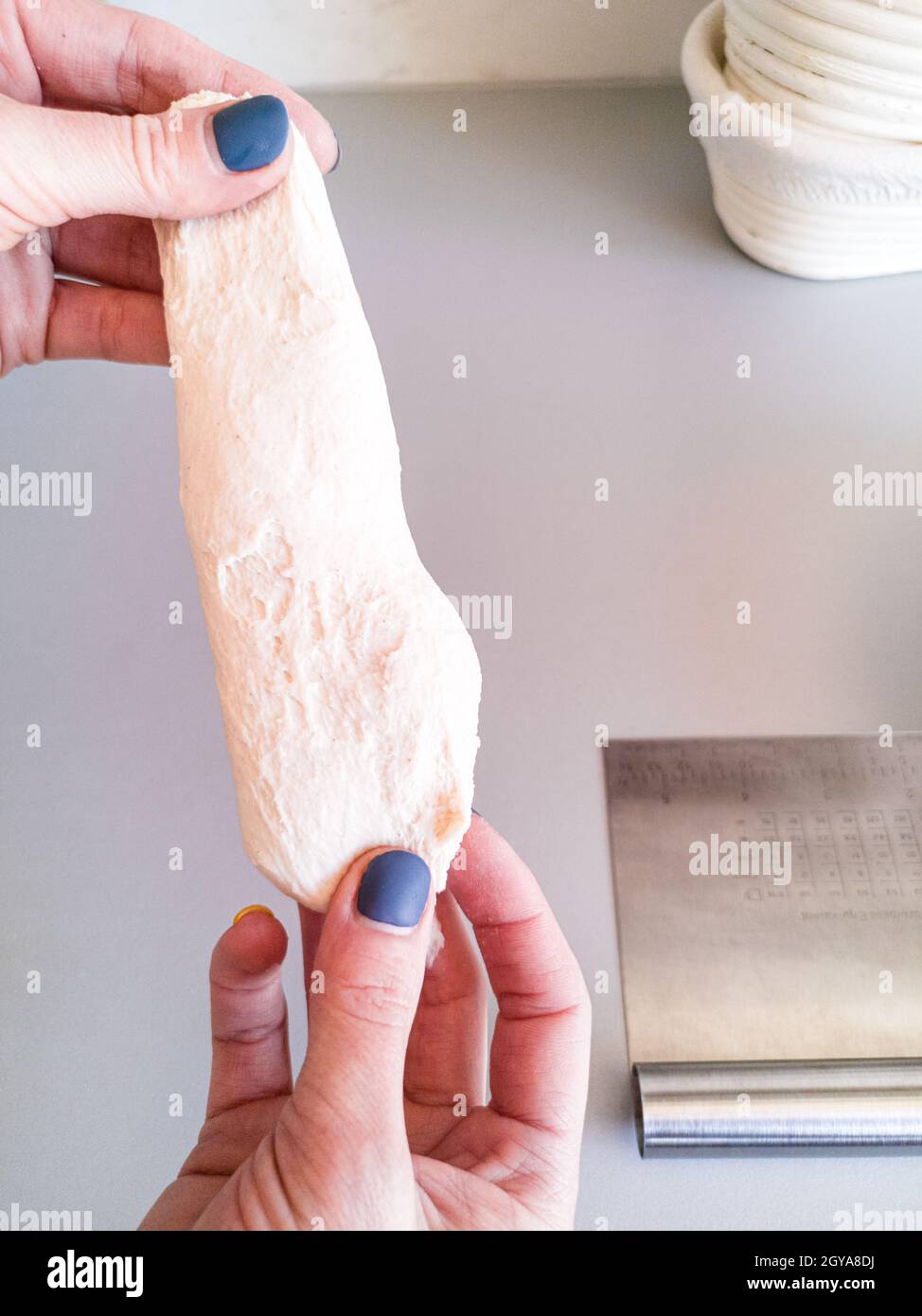 Woman's hands stretch a piece of dough to check the quality of flour ...