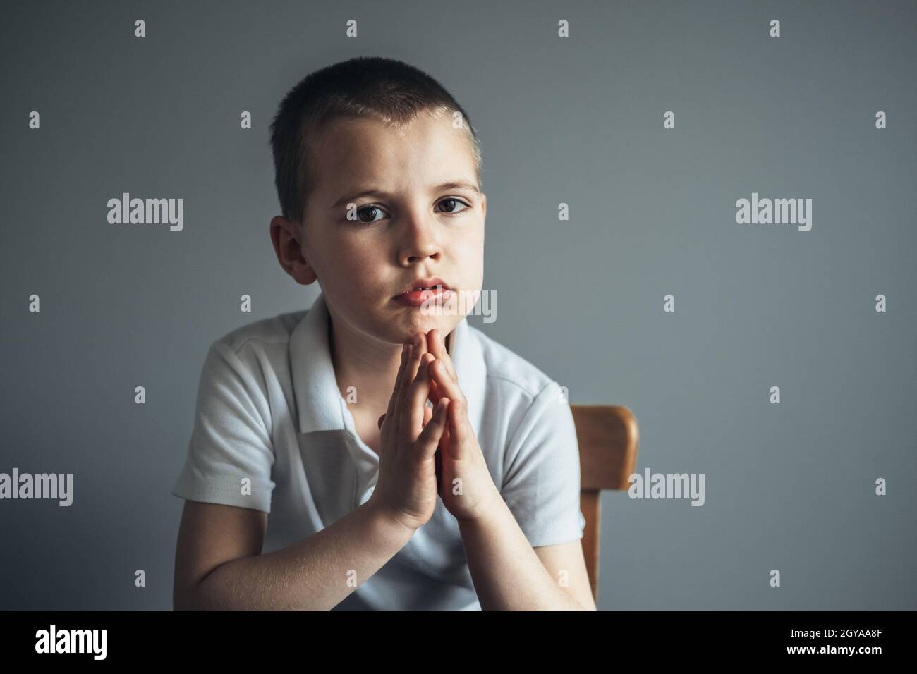 Portrait of little pensive boy sitting on the chair Stock Photo - Alamy