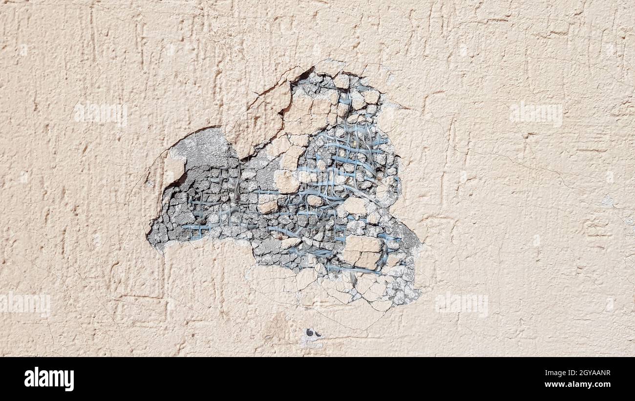 dent on a yellow concrete wall. Hole in the wall with foam insulation ...