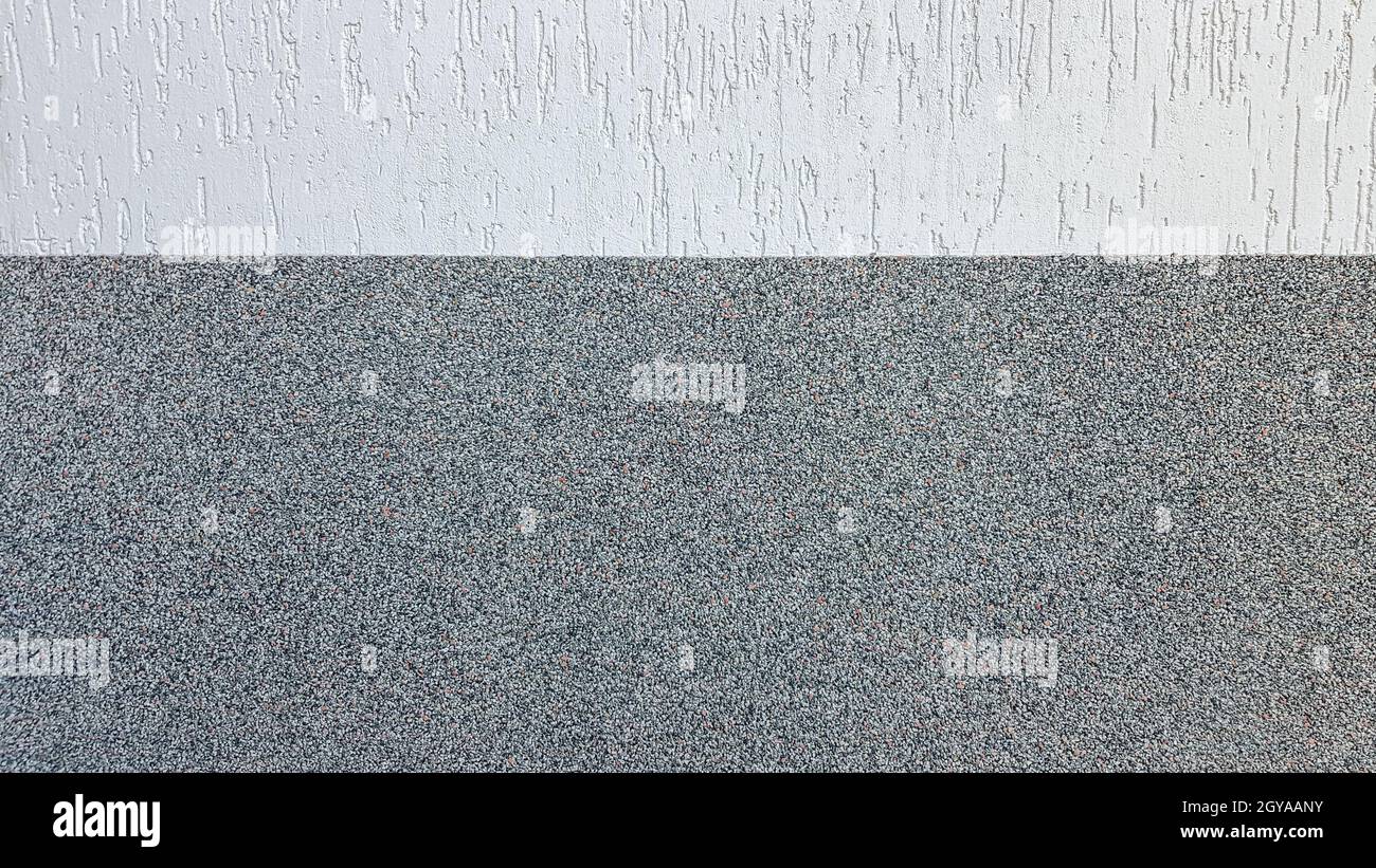 Gray marble chips and decorative light stucco on the wall divided by a ...