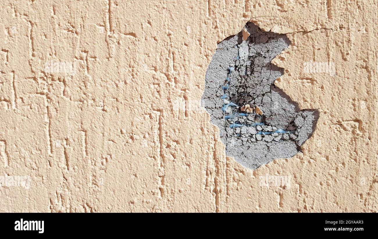 dent on a yellow concrete wall. Hole in the wall with foam insulation ...