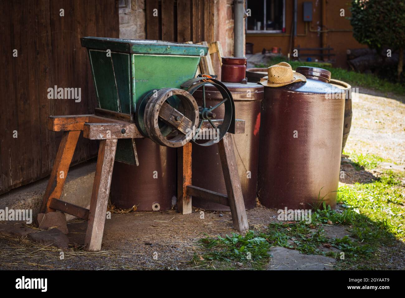 agricultural objects in the yard of an old farmhouse with grain crasher ...