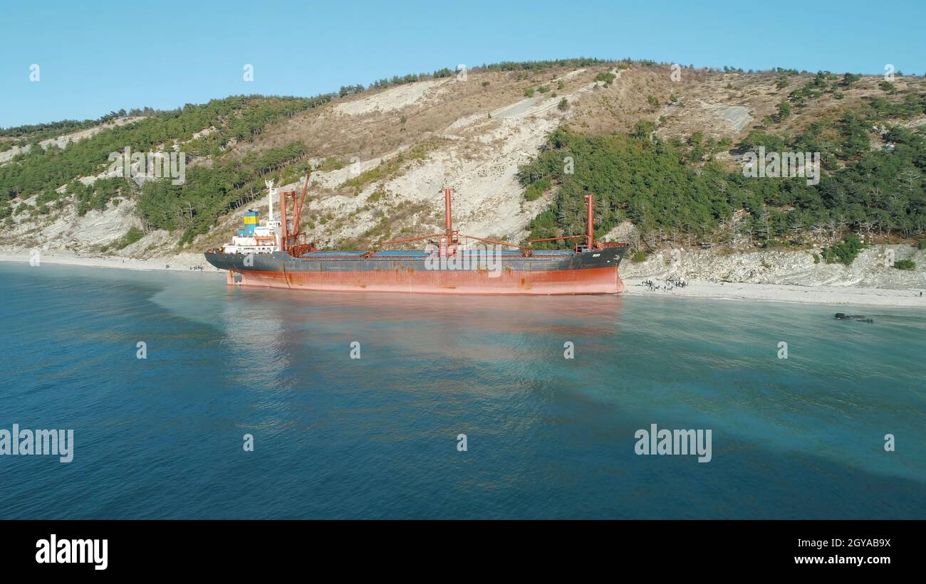 Large red tanker ship in the sea near the shore in clear blue water ...