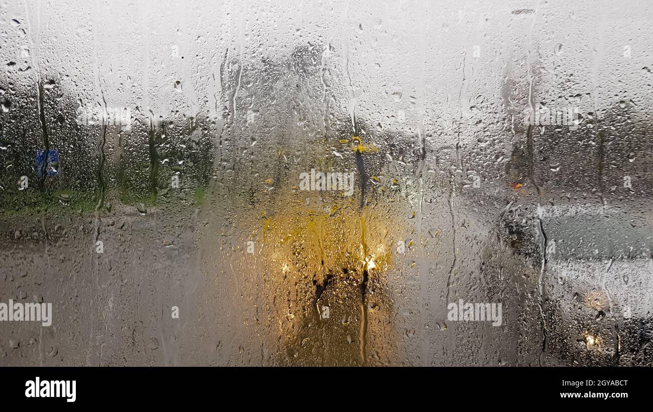 Rain on the rear window of a car in autumn. Inside view of the road ...