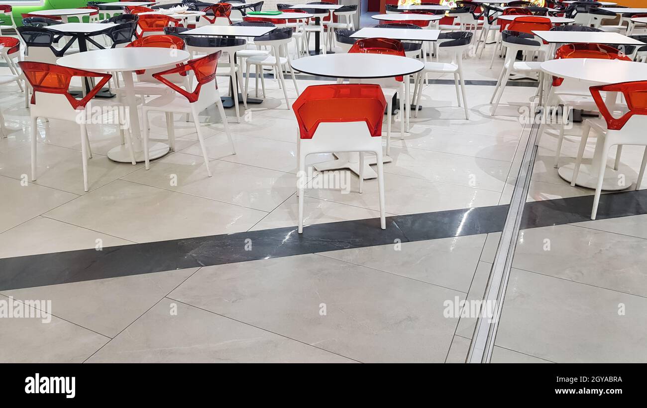 food area with plastic white and red tables and chairs in a mall ...