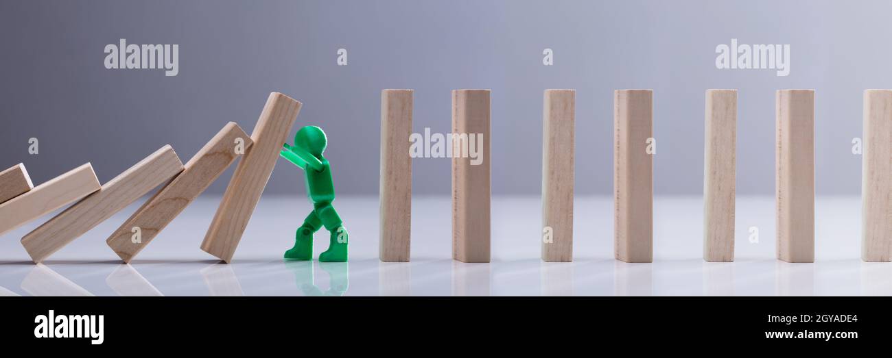 Falling Domino Risk Stop. Green Person Intervention Stock Photo - Alamy