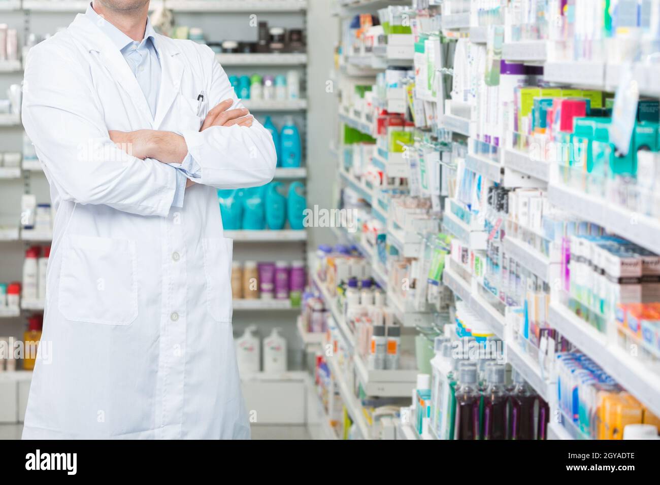 Portrait of smiling mid adult male pharmacist standing arms crossed in ...