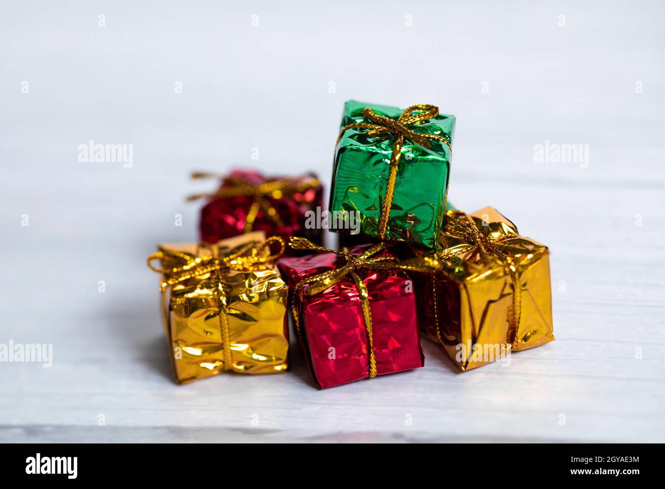Pile of colored shiny gift boxes with copy space on white wood ...