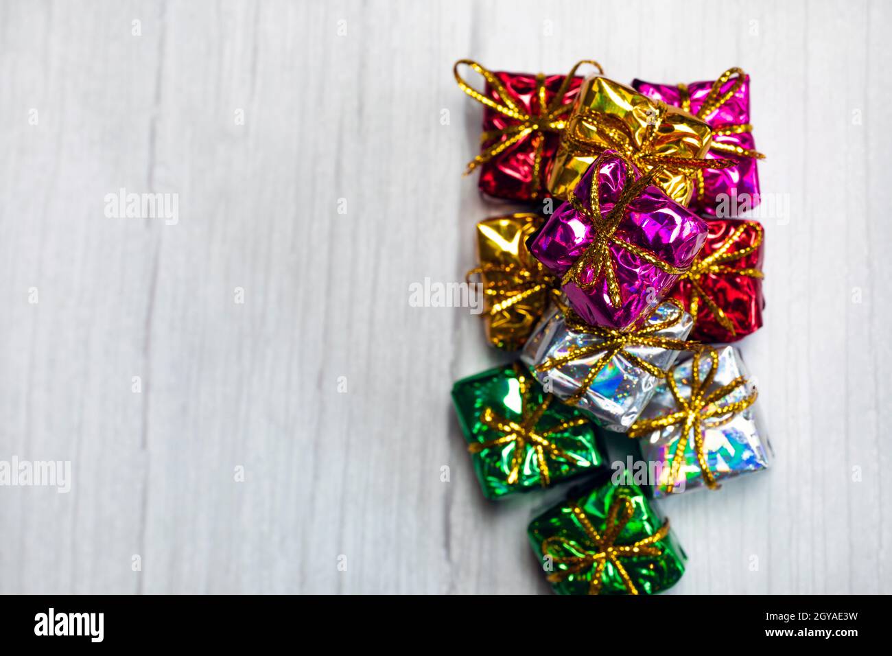 Pile of colored shiny gift boxes with copy space on white wood ...