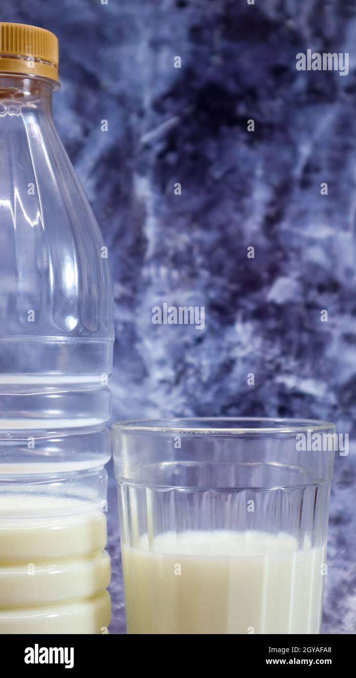 A plastic bottle of fresh regular milk and a glass beaker on a dark ...