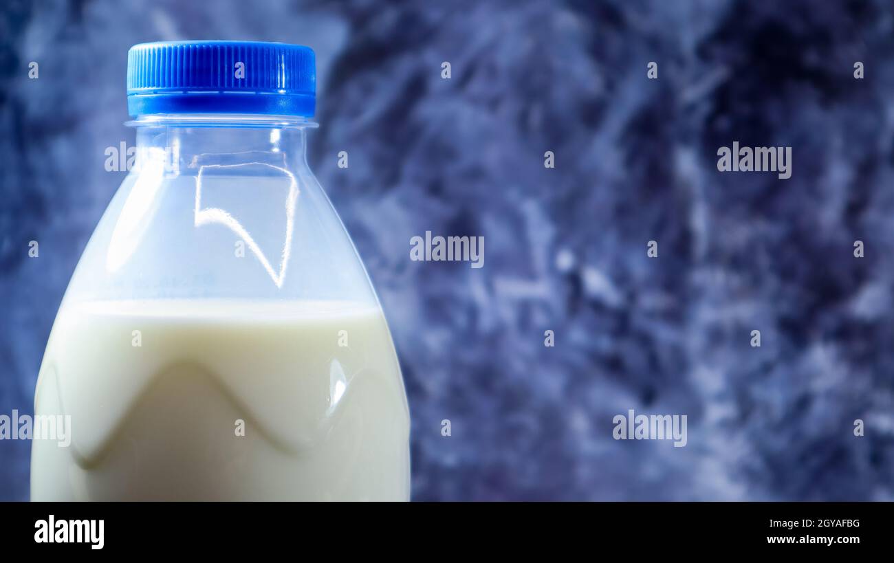 A plastic bottle of fresh regular milk on a dark gray marbled or ...