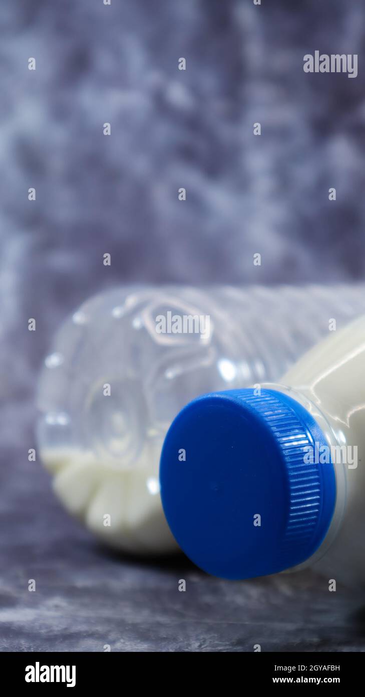 A plastic bottle of fresh regular milk on a dark gray marbled or ...