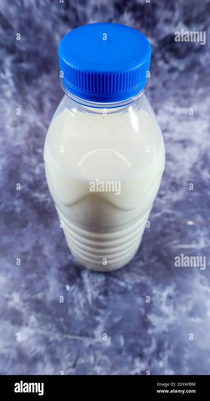 A plastic bottle of fresh regular milk on a dark gray marbled or ...
