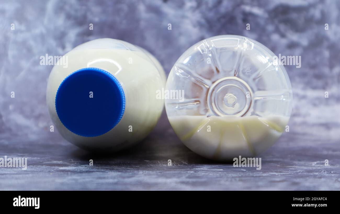 A half-empty and full plastic bottle of fresh regular milk lies on a ...
