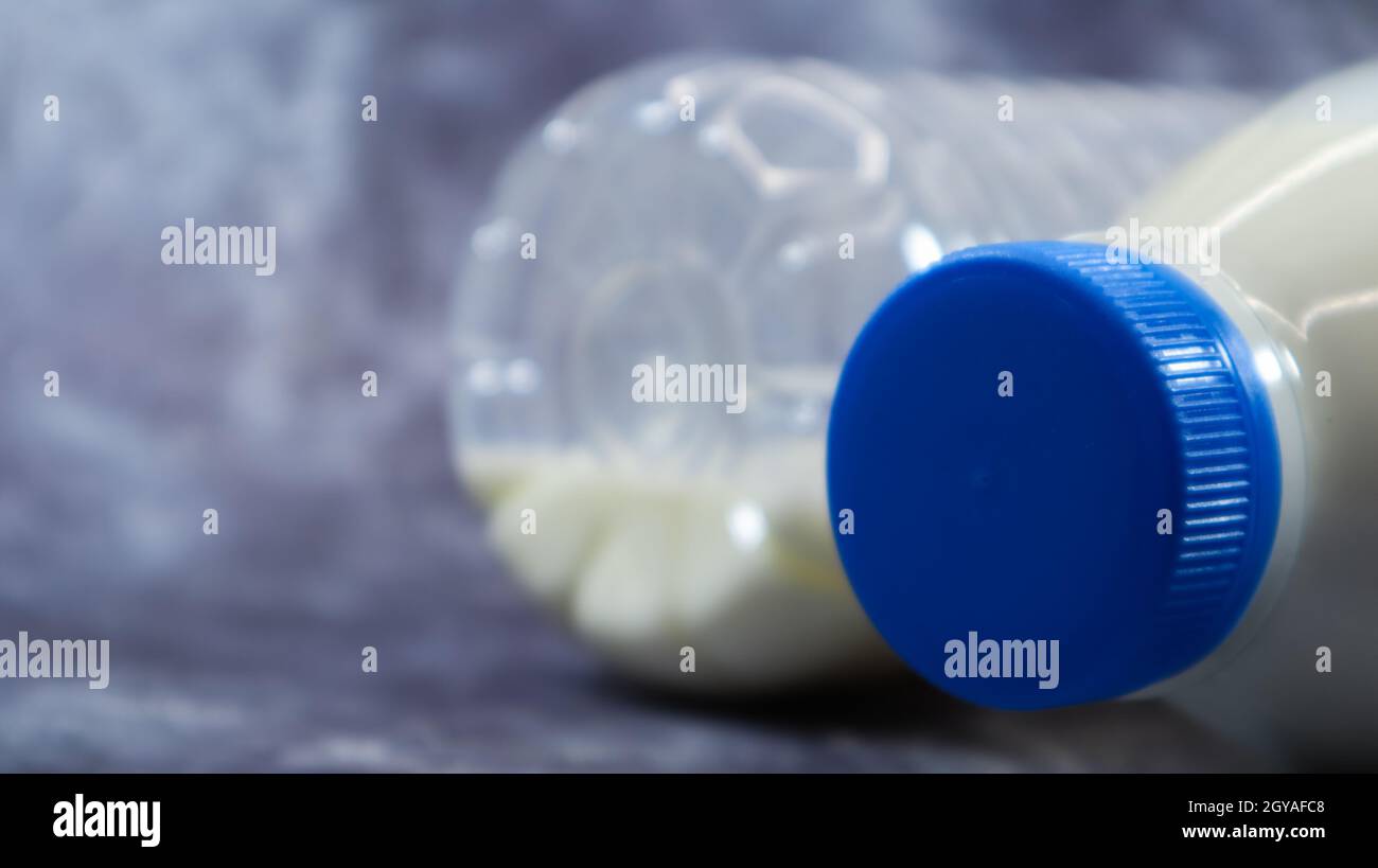 A half-empty and full plastic bottle of fresh regular milk lies on a ...