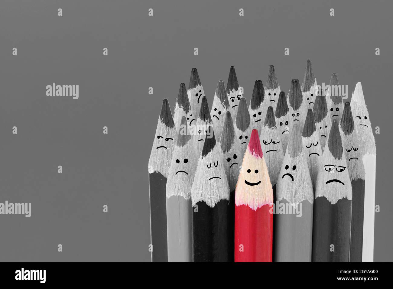 Bright colored smiling pencil among big set of black and white sad ...