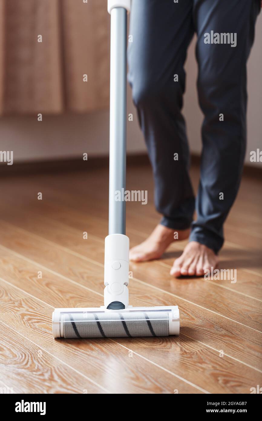 A cordless vacuum cleaner cleans the parquet in the living room with ...