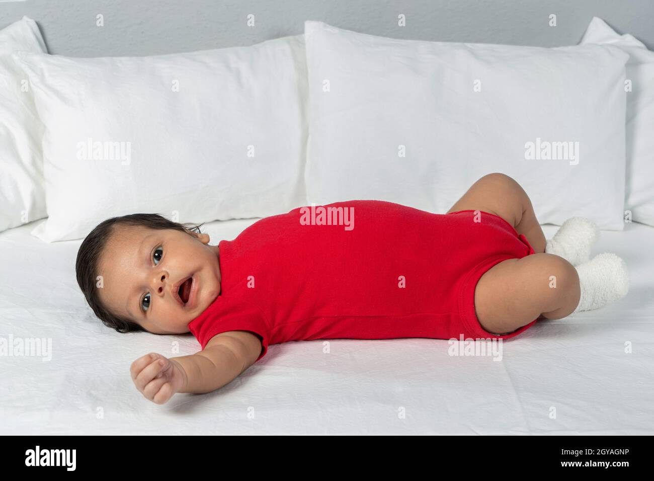 Infant child lying on his back. Wearing red clothes Stock Photo - Alamy