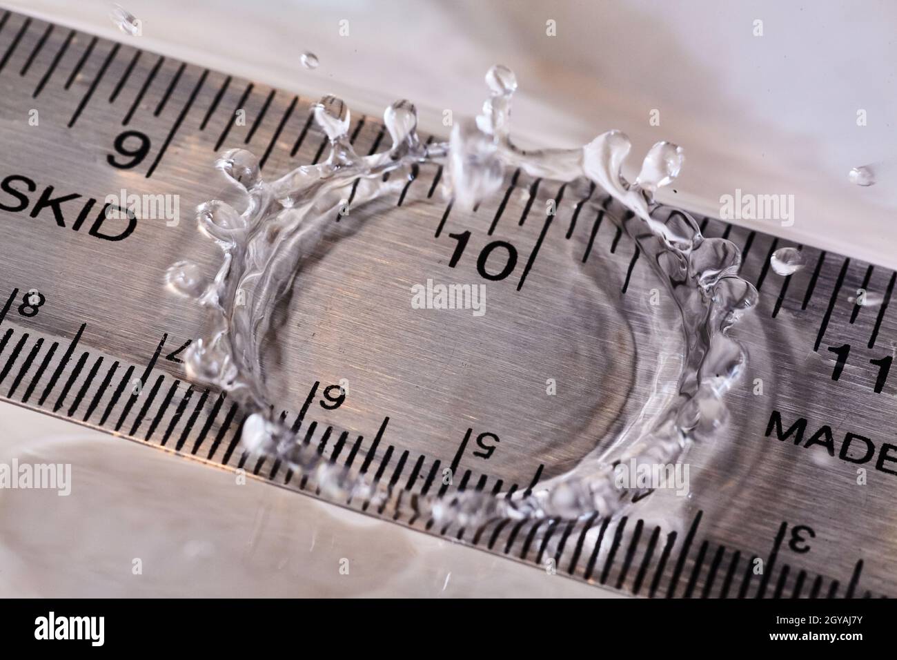 A circular waterdrop atop surface of a ruler at the ten inch mark Stock ...