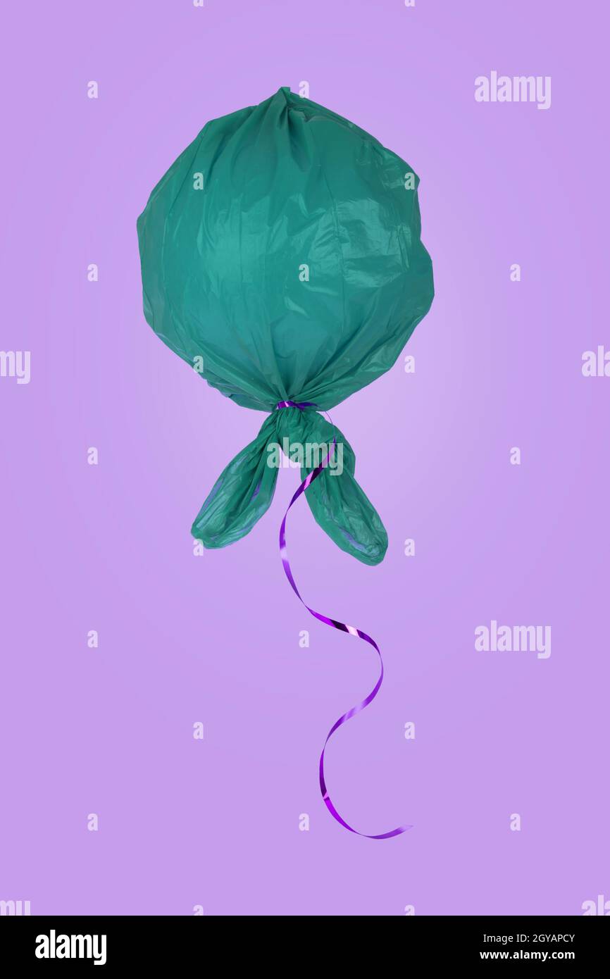Green garbage bag balloon flying isolated on a light purple background ...