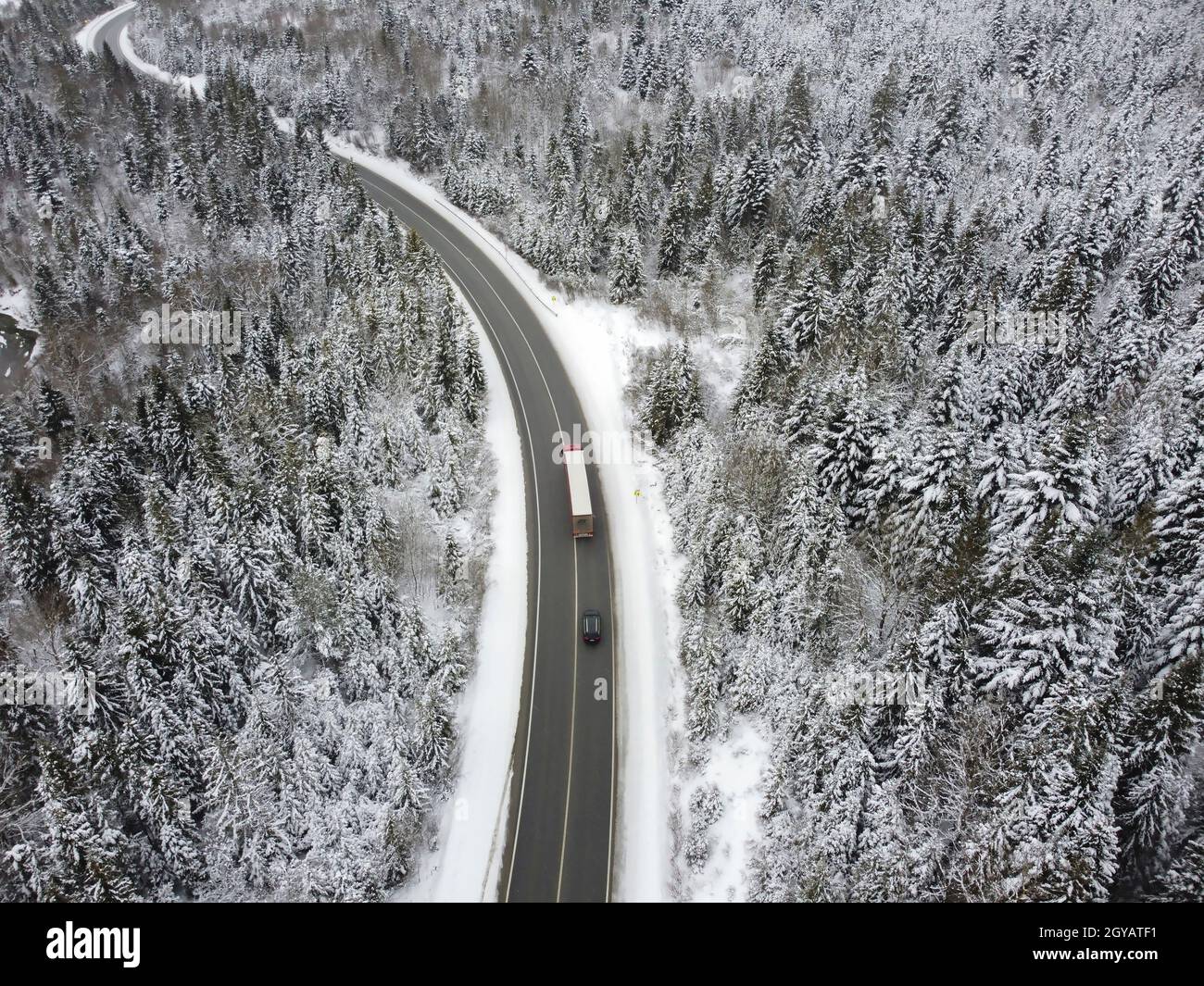 Winding road through the woods in winter. asphalt through the pass to ...