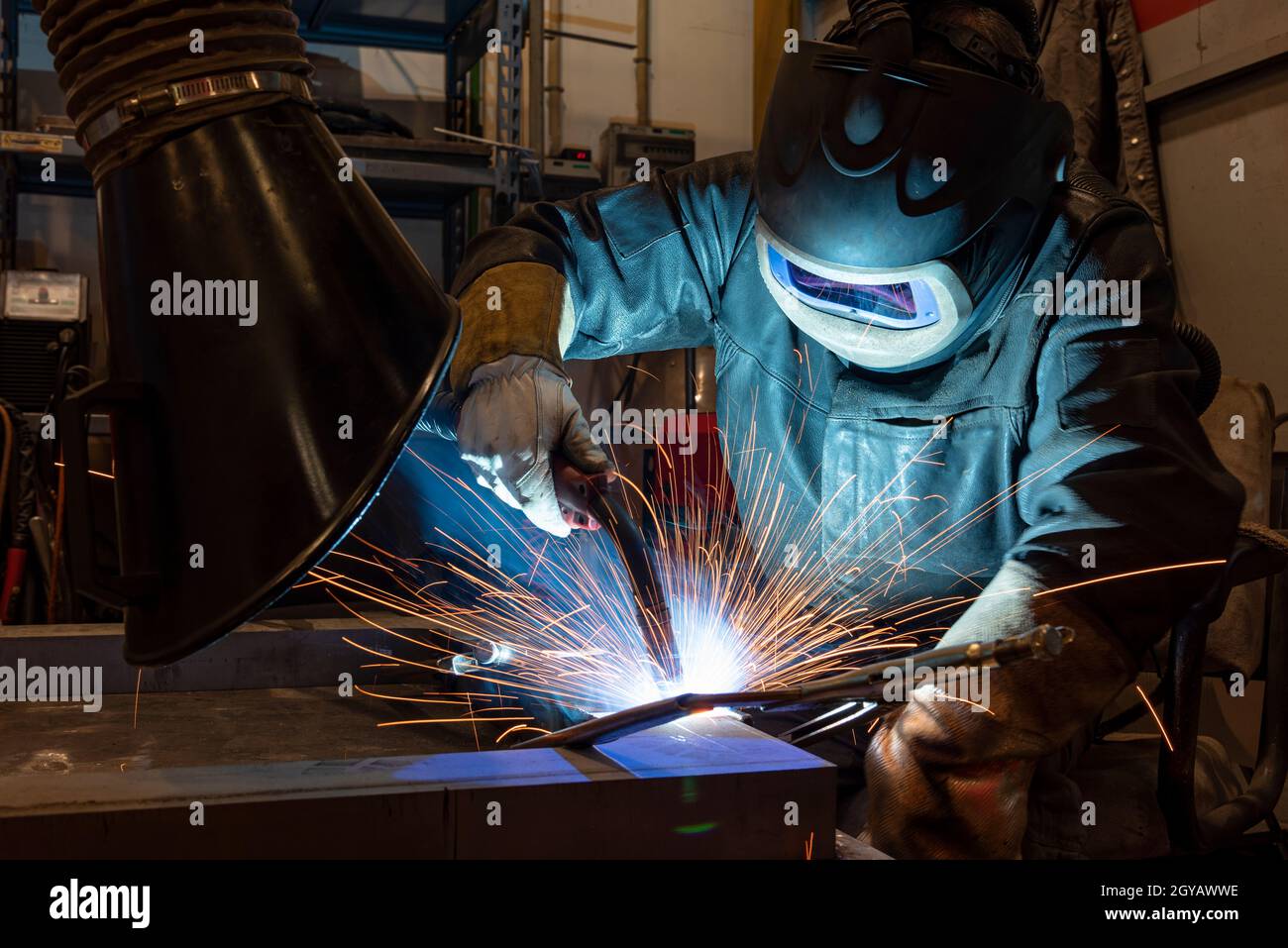 welder with protective mask welding metal and sparks. Industrial steel ...