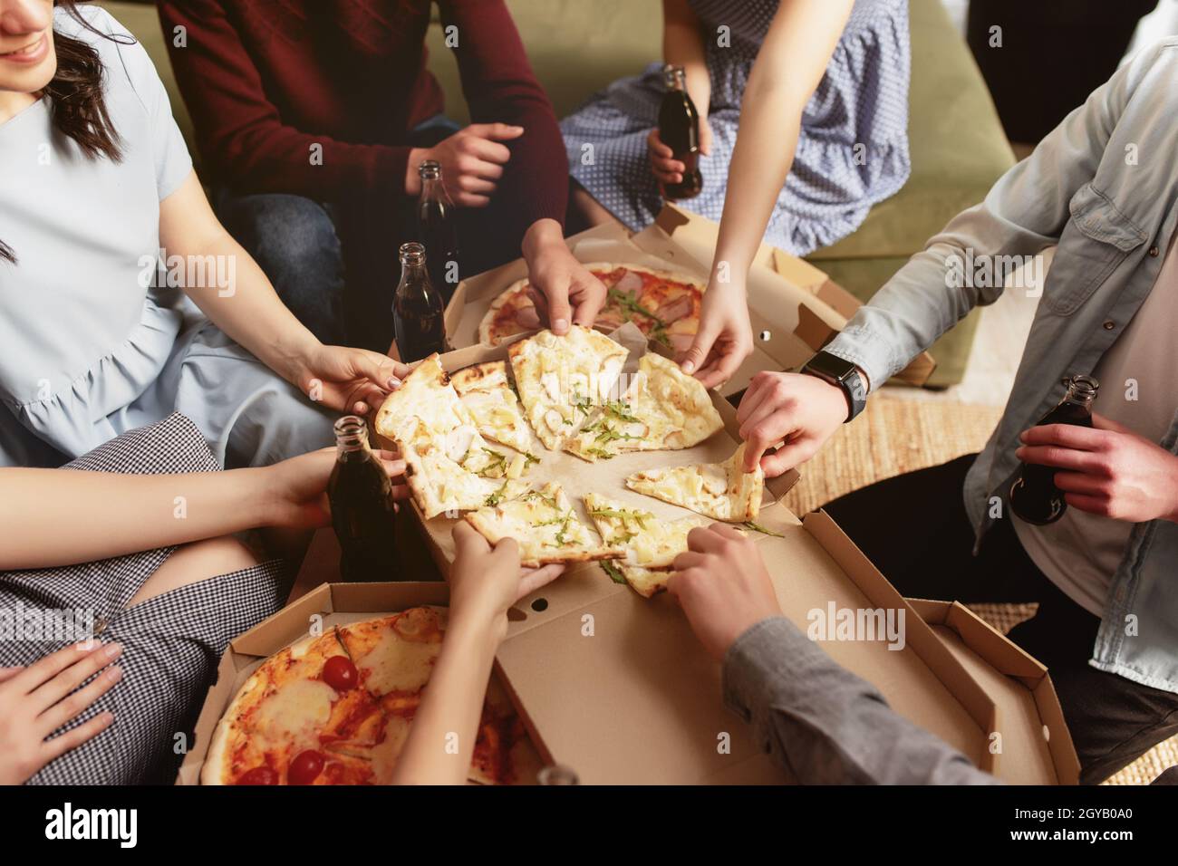 A pizza party, a group of friends chatting and happily eating pizza at ...