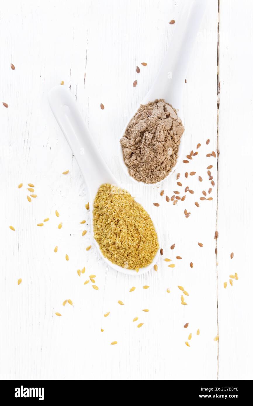 Flaxseed bran and flour in two spoons, seeds on a wooden board ...