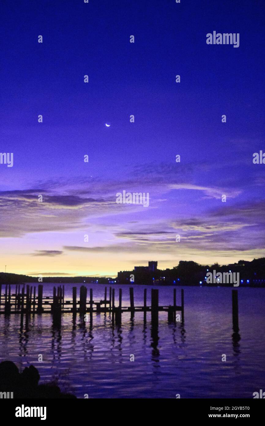 Infrared of empty docks and silhouette of a city with a crescent moon ...