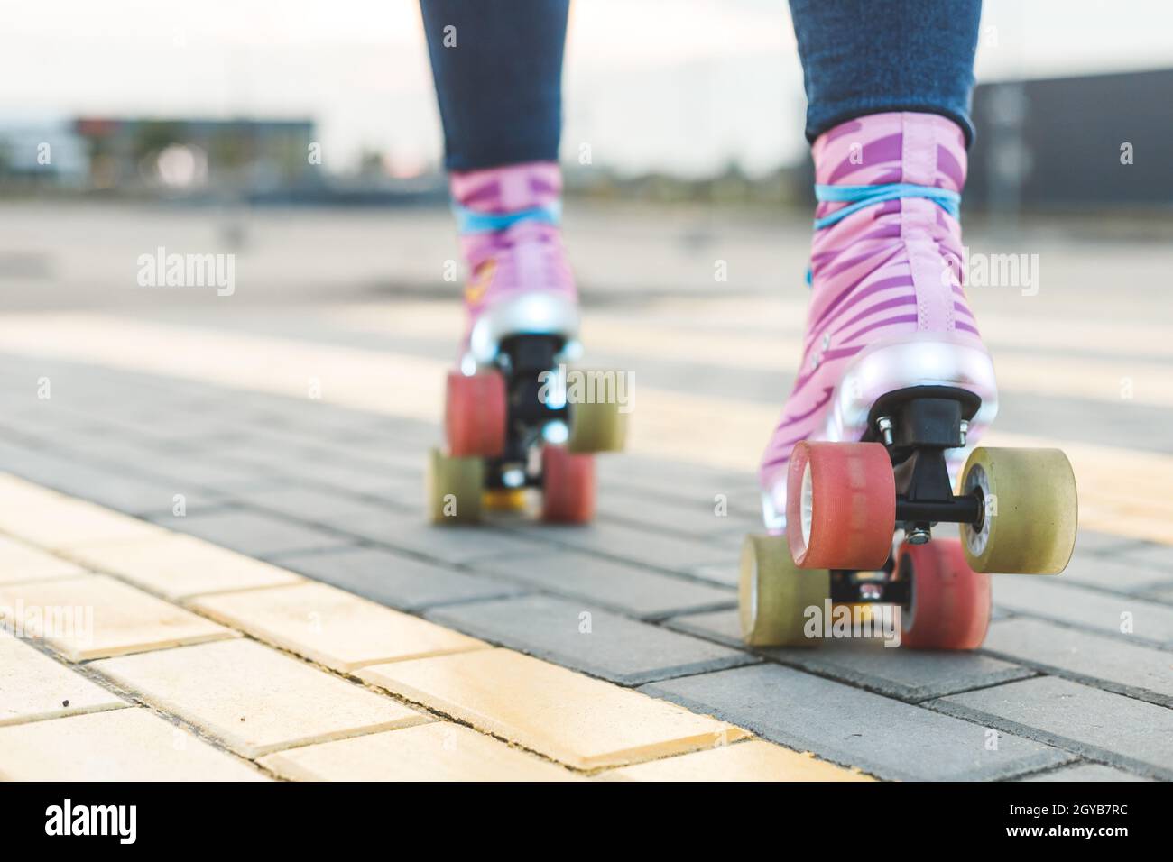Young woman legs riding on colorful roller-skates. Back bottom view ...