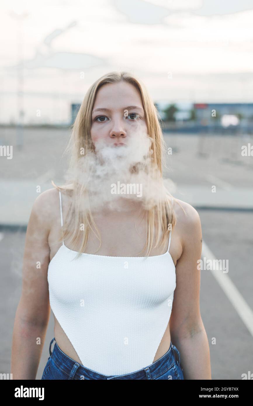Blonde woman in city with electronic cigar ready for vaping Stock Photo ...
