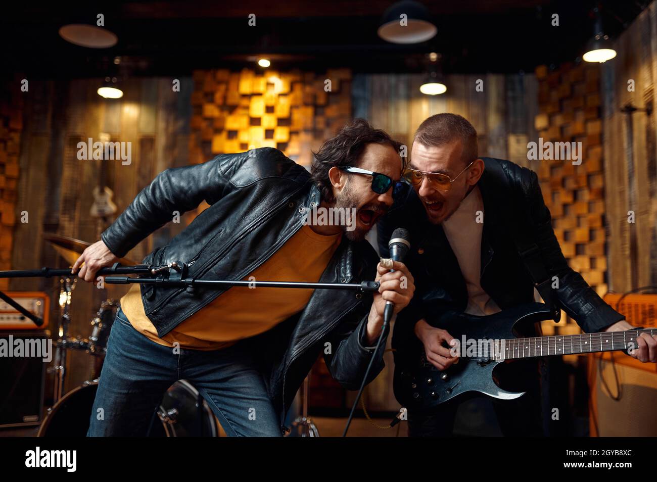 Two musicians at microphone, music performing on stage. Rock band ...