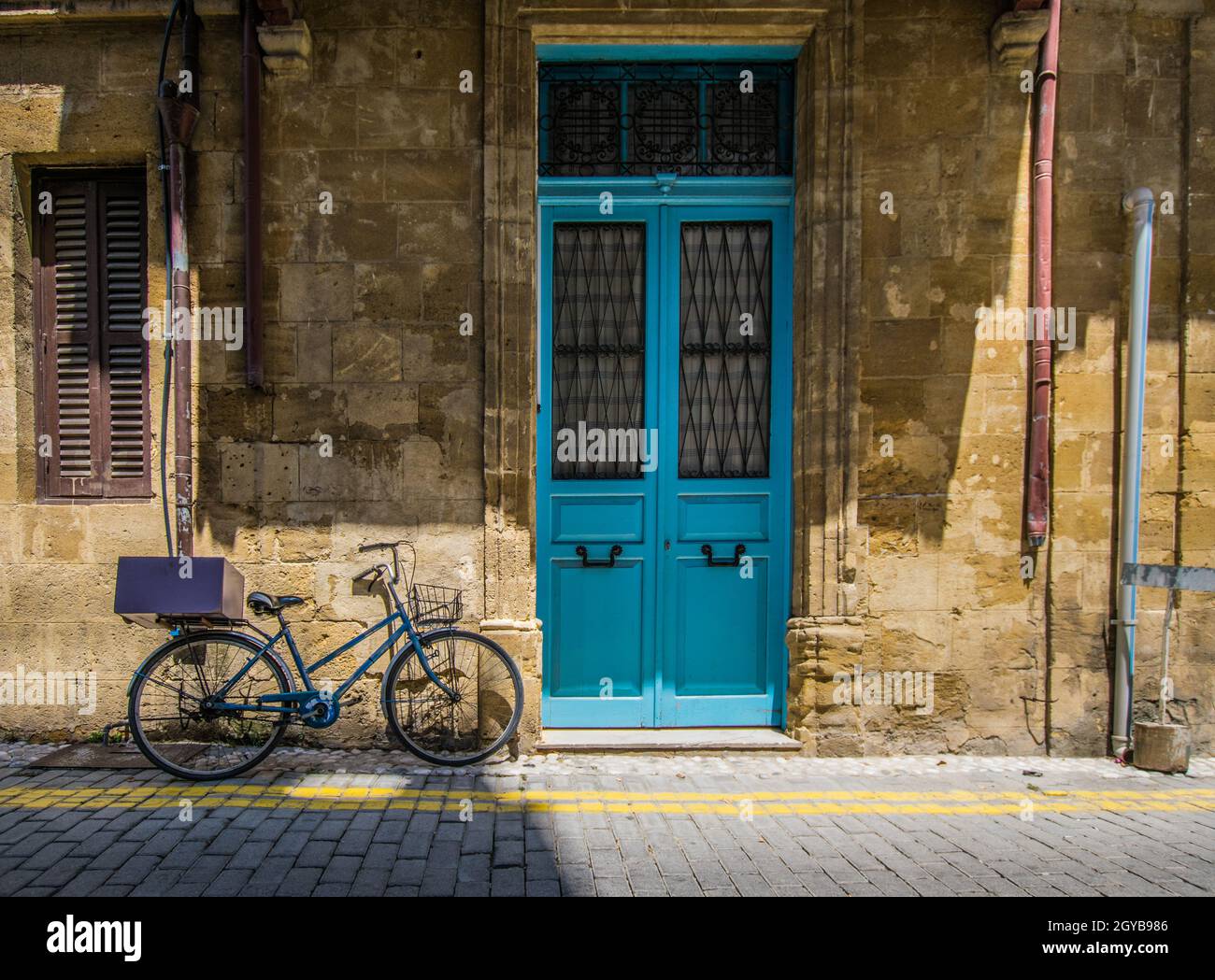 Blue bicycle next to Blue tall traditional Greek door of a stone house ...