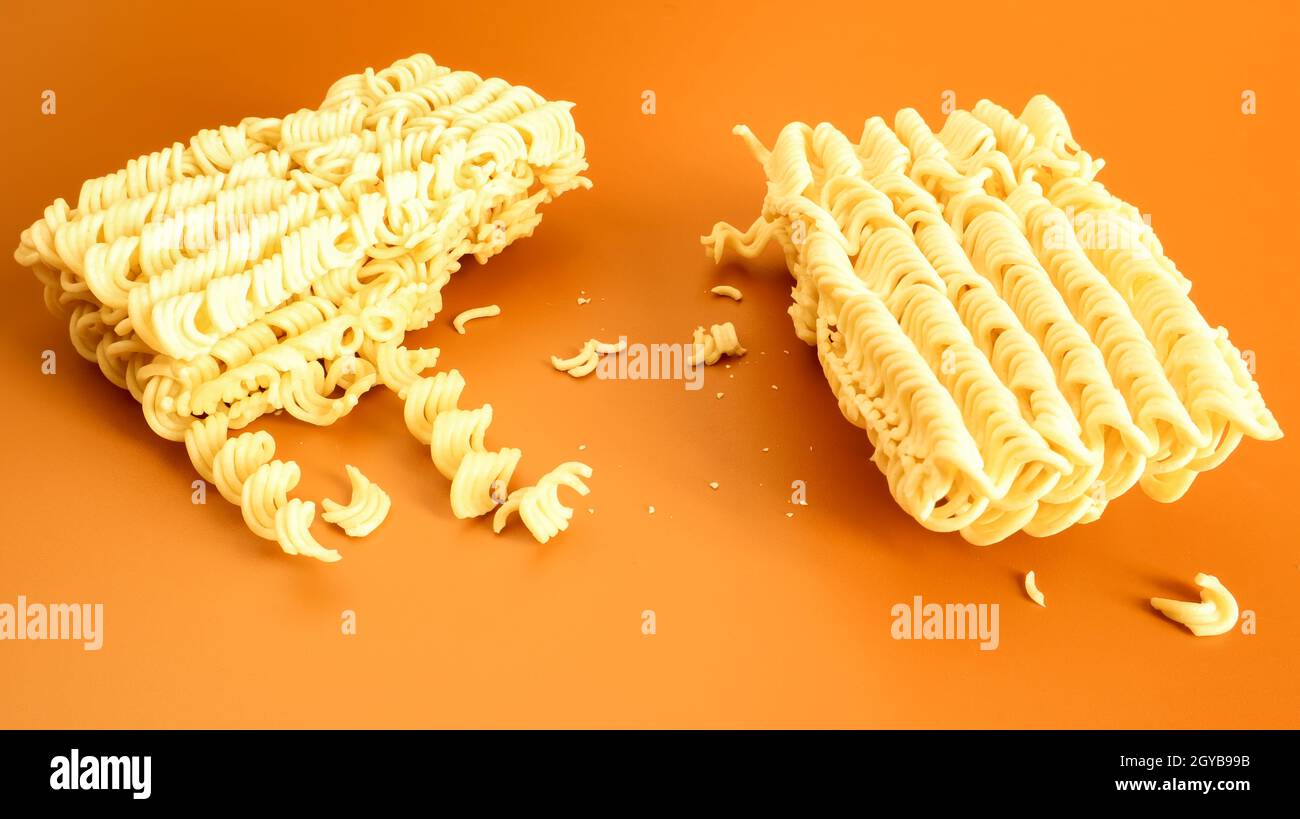 Instant noodles split in half on a yellow background. The concept of ...