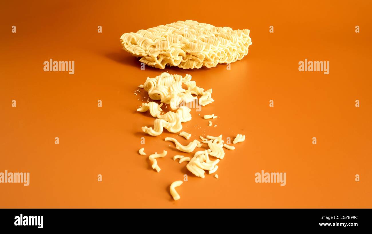 Instant noodles split in half on a yellow background. The concept of ...
