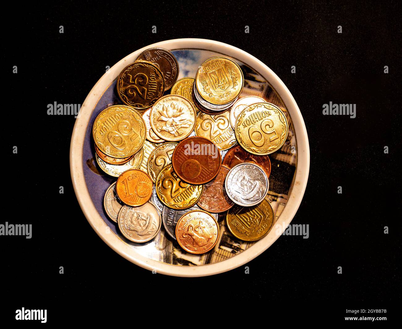 Small money coins in a plate on a black background. Eurocent. Ukrainian ...